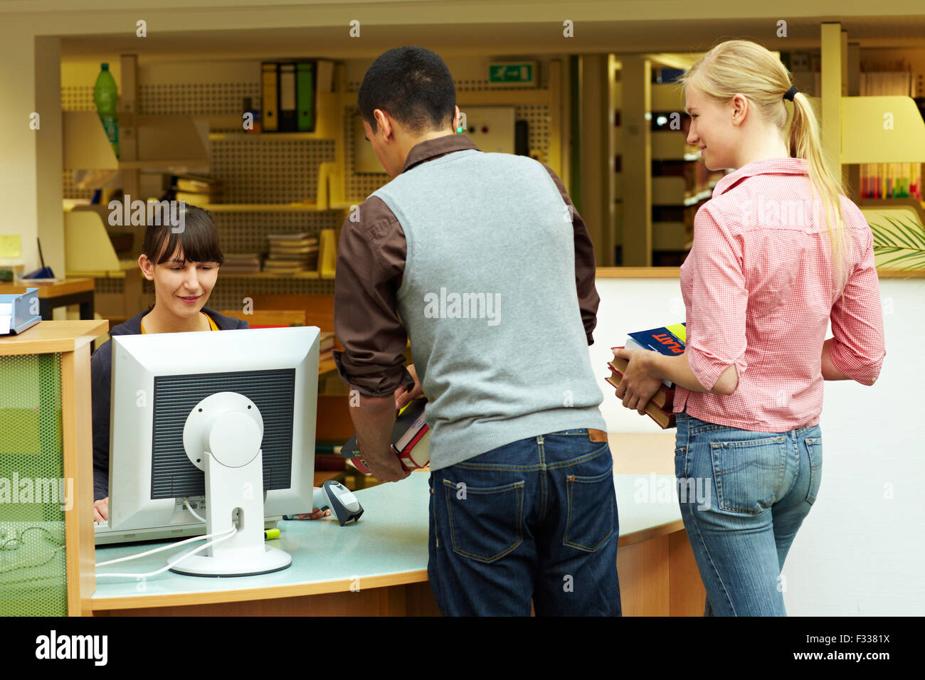 Students waiting while checking out books in library Stock Photo - Alamy