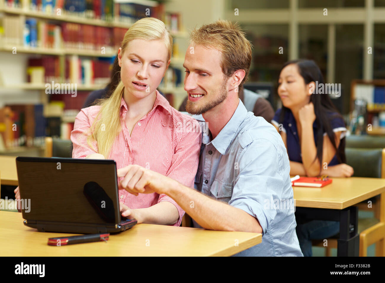 Student helping each other in a library Stock Photo - Alamy