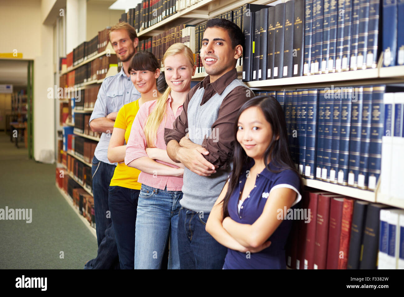 Group of students leaning on book shelf Stock Photo - Alamy