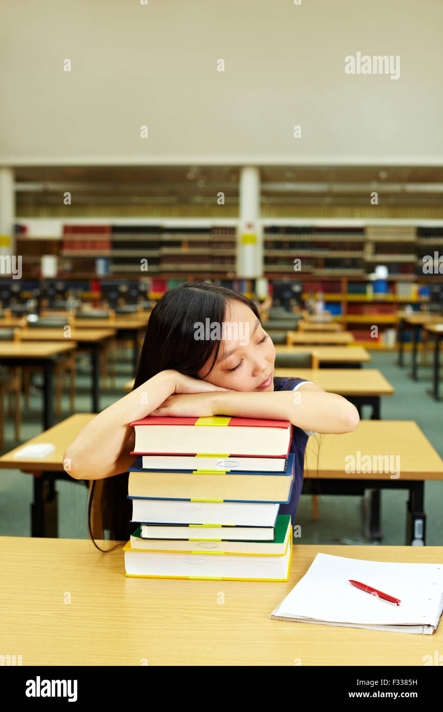 Student sleeping in library on stack of books Stock Photo - Alamy