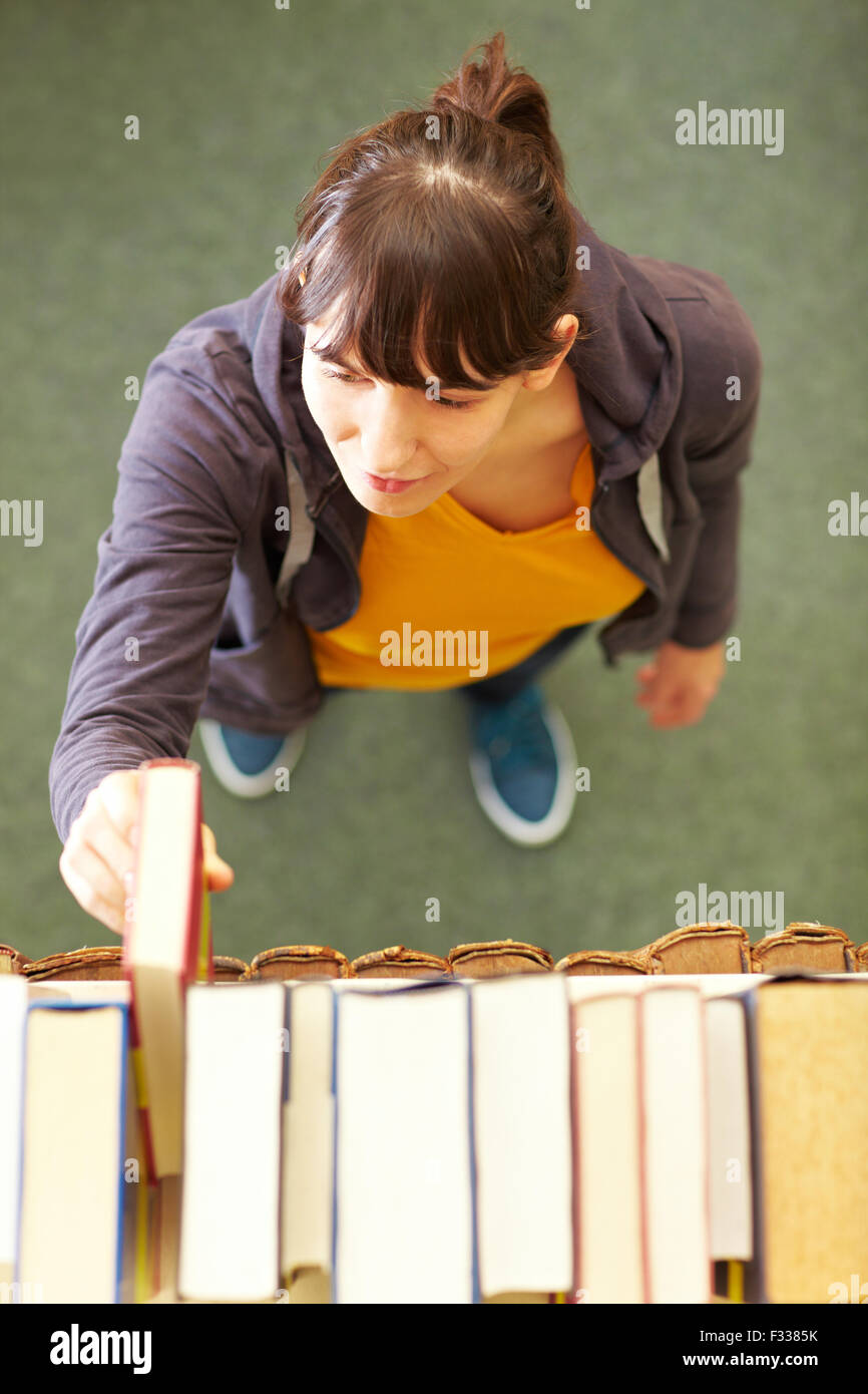 Student taking a book from shelf in library Stock Photo - Alamy