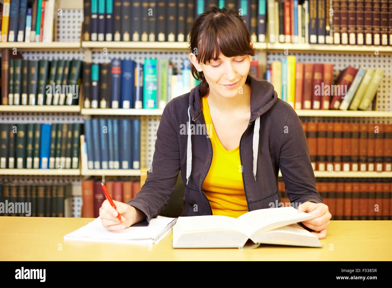 Student reading a book and taking notes Stock Photo - Alamy