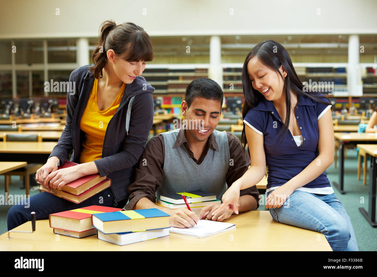 Three happy students learning in university library Stock Photo - Alamy