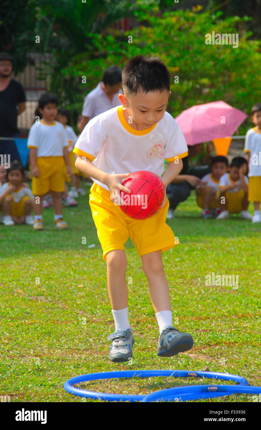 Kindergarten children competing in jumping ball race at their sport day ...