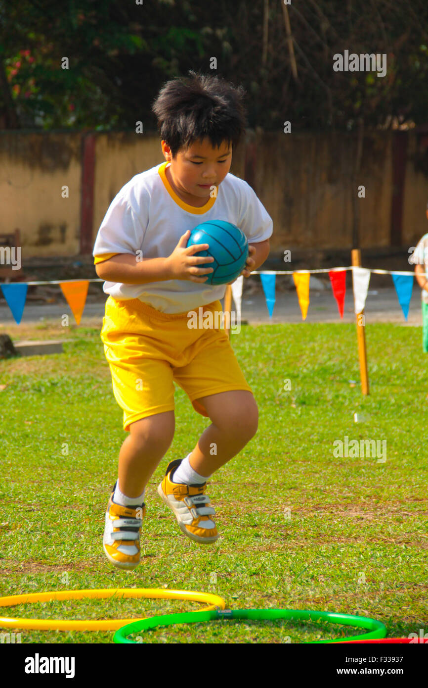 Kindergarten children competing in jumping ball race at their sport day ...
