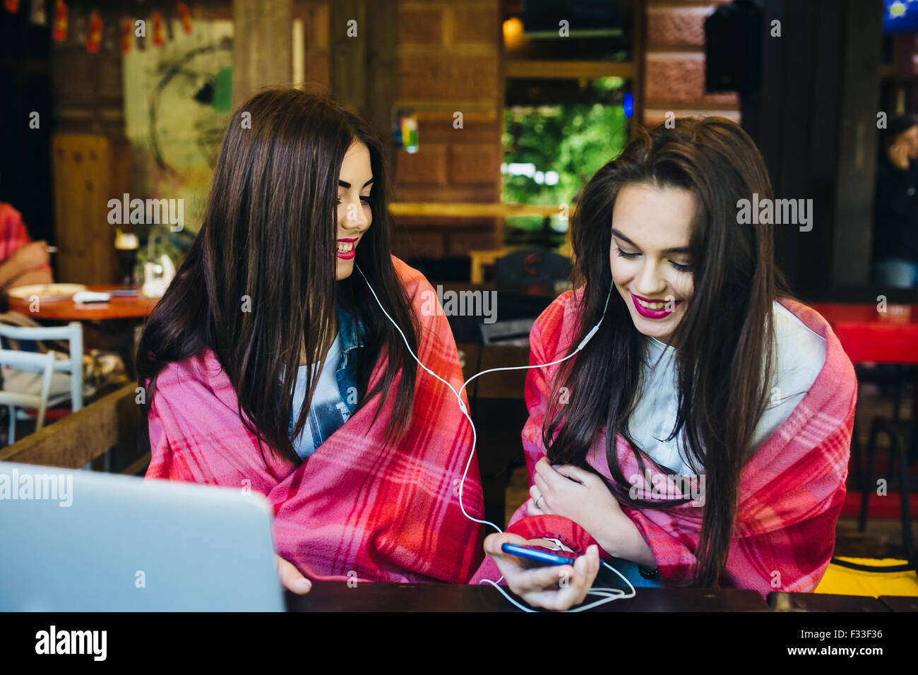 Two girl sitting listening music with a smartphone Stock Photo - Alamy