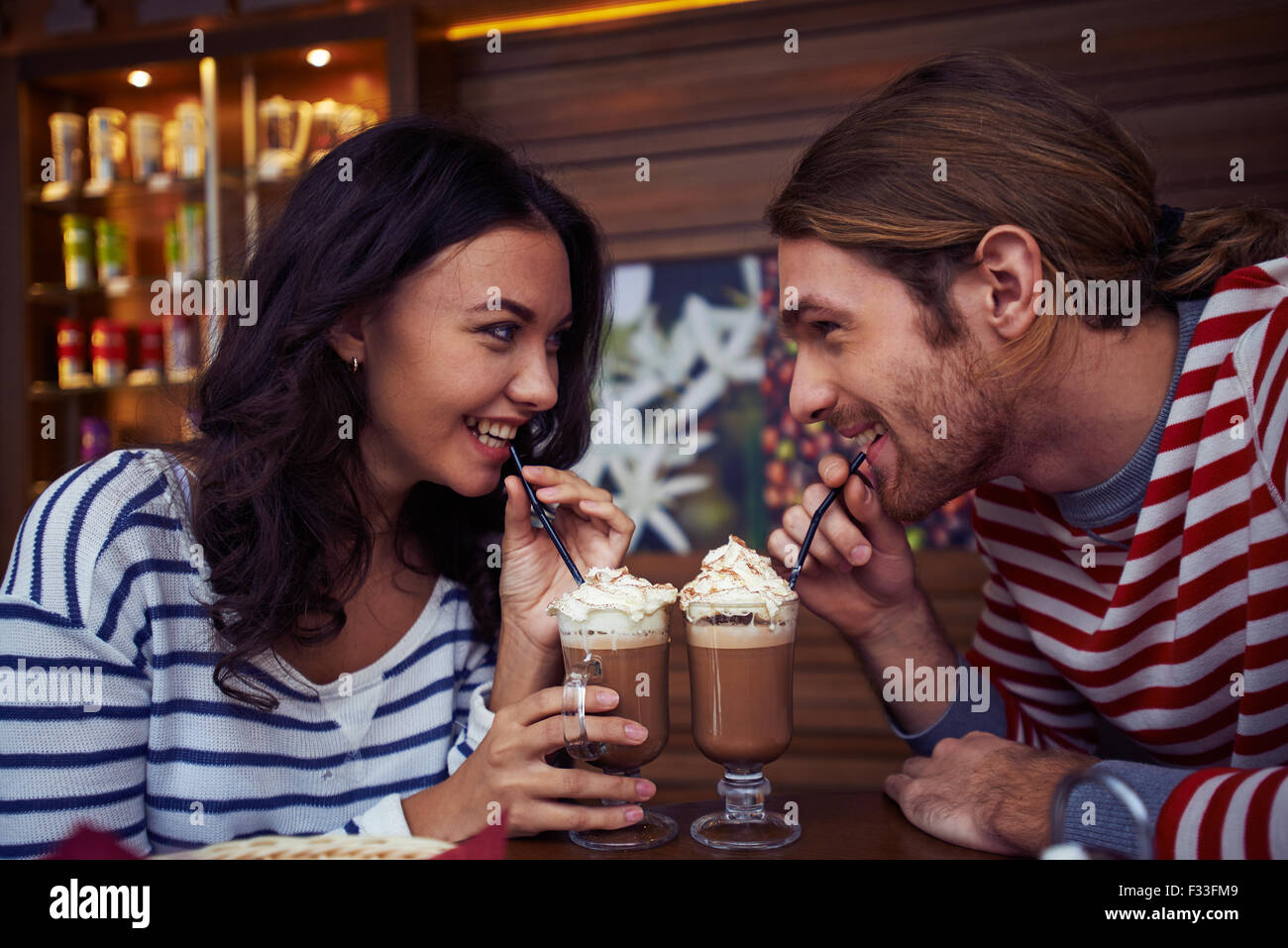 Flirty young couple drinking latte in cafe Stock Photo - Alamy