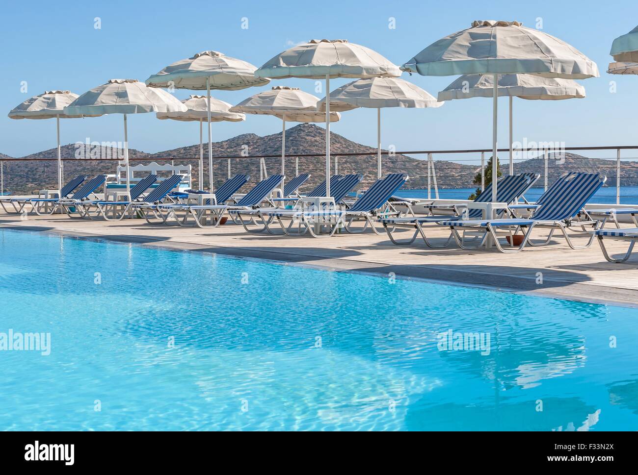 Swimming pool with sun loungers and parasols Stock Photo - Alamy