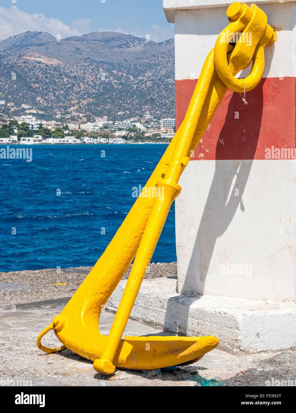 Yellow anchor resting against the foot of a habour light Stock Photo ...