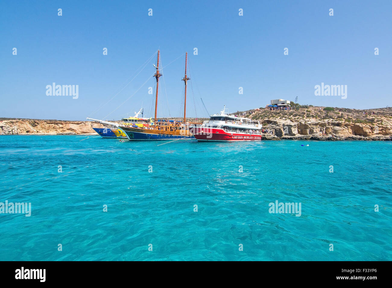 Tour boats in the clear turquoise water and arid landscape of popular ...
