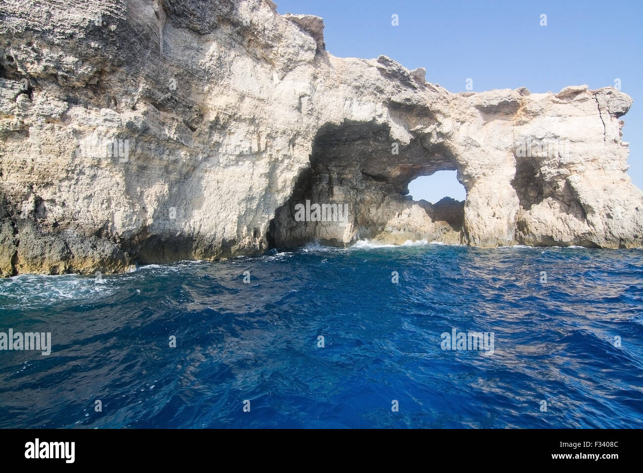Coastal view of steep limestone rocks with caves and turquoise blue ...