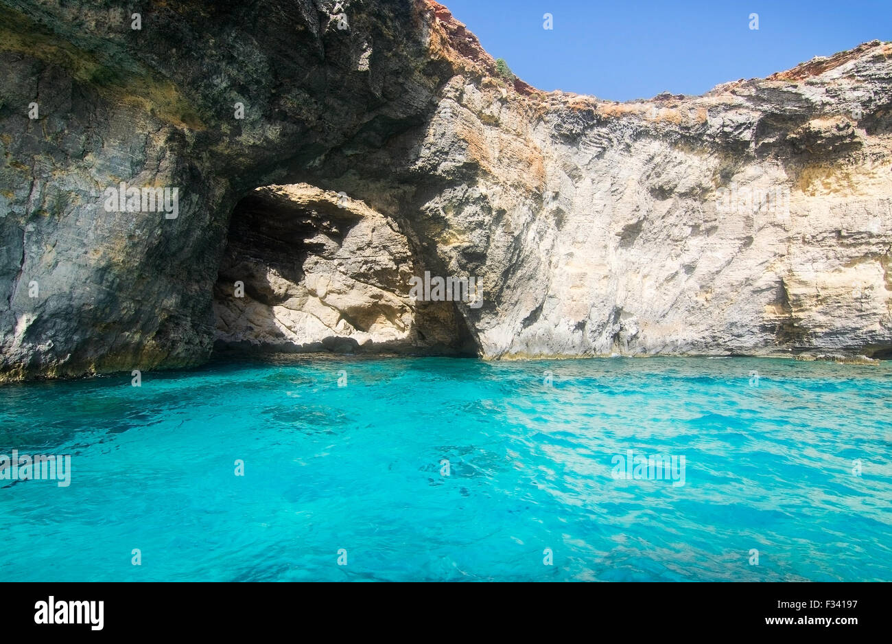 Coastal view of steep limestone rocks with caves and turquoise blue ...