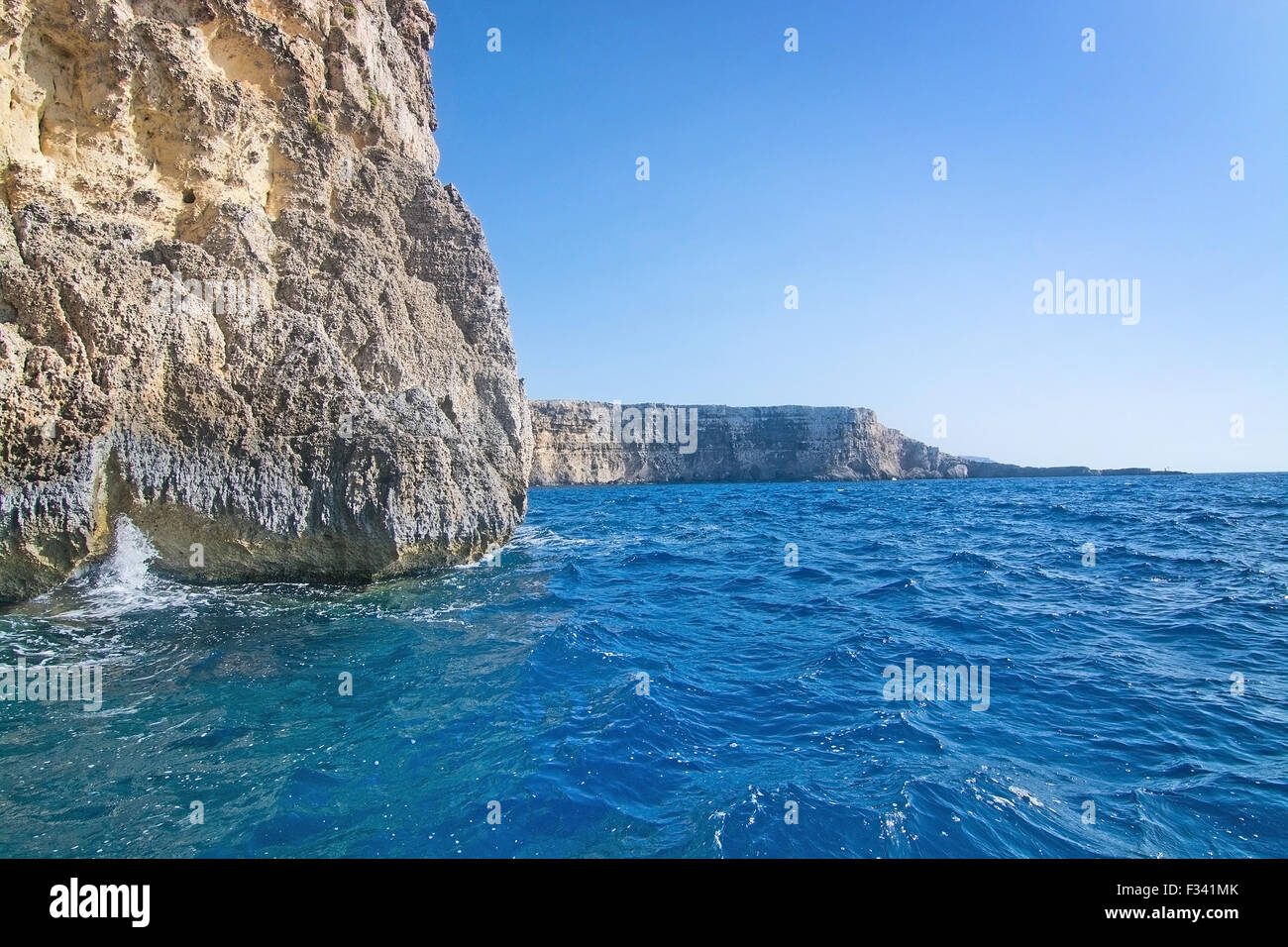 Coastal view of steep limestone rocks with caves and turquoise blue ...