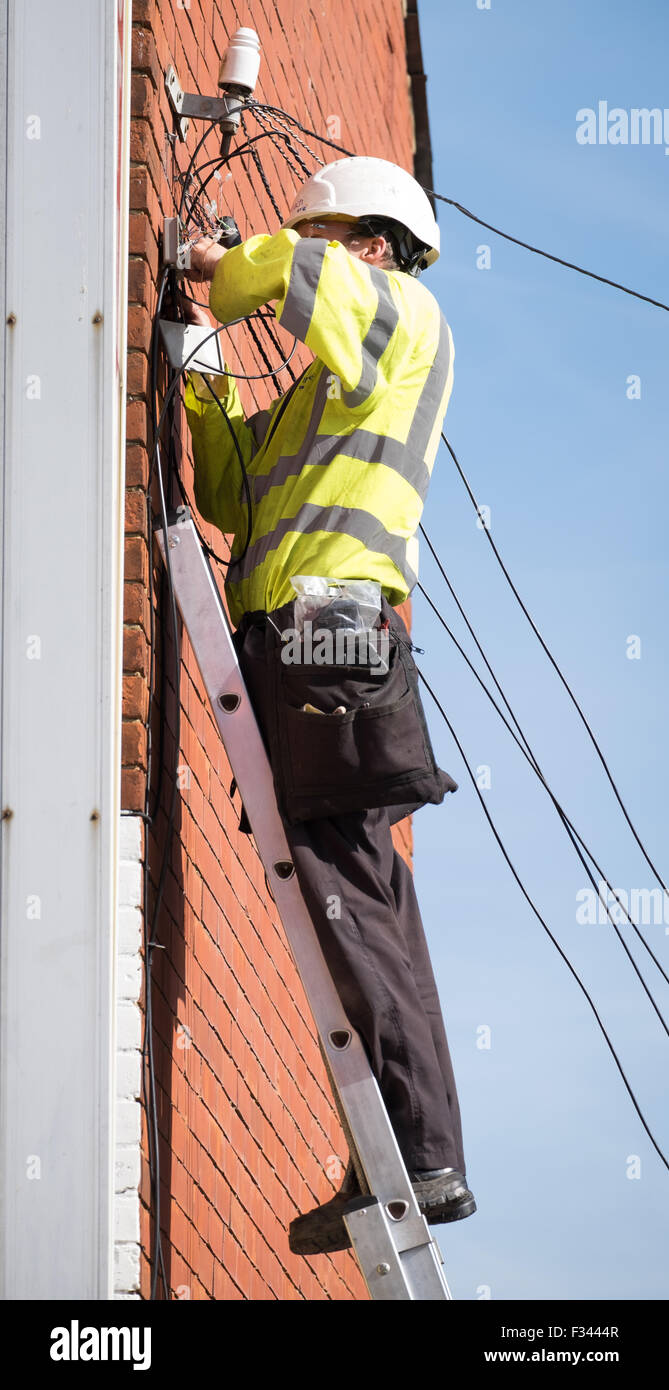 A BT Openreach engineer working up a ladder fixing a phone line Stock ...