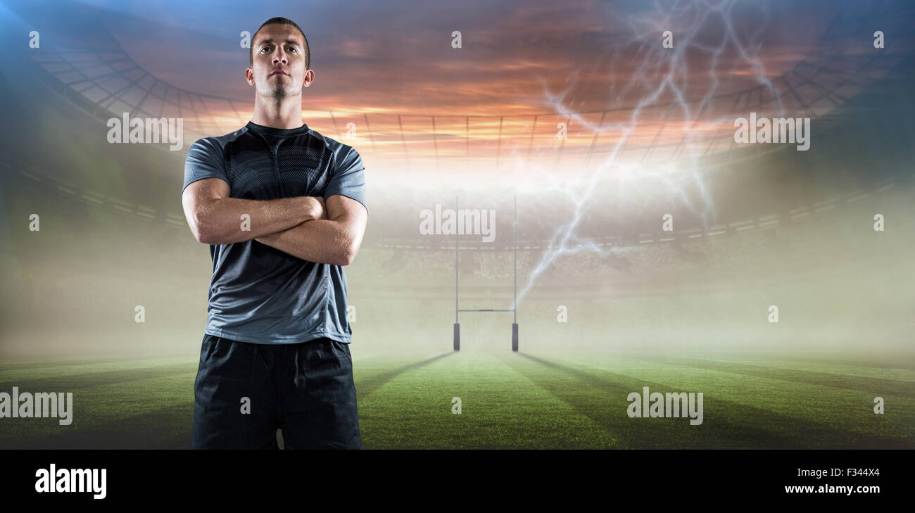 Composite image of full length of confident rugby player with arms ...