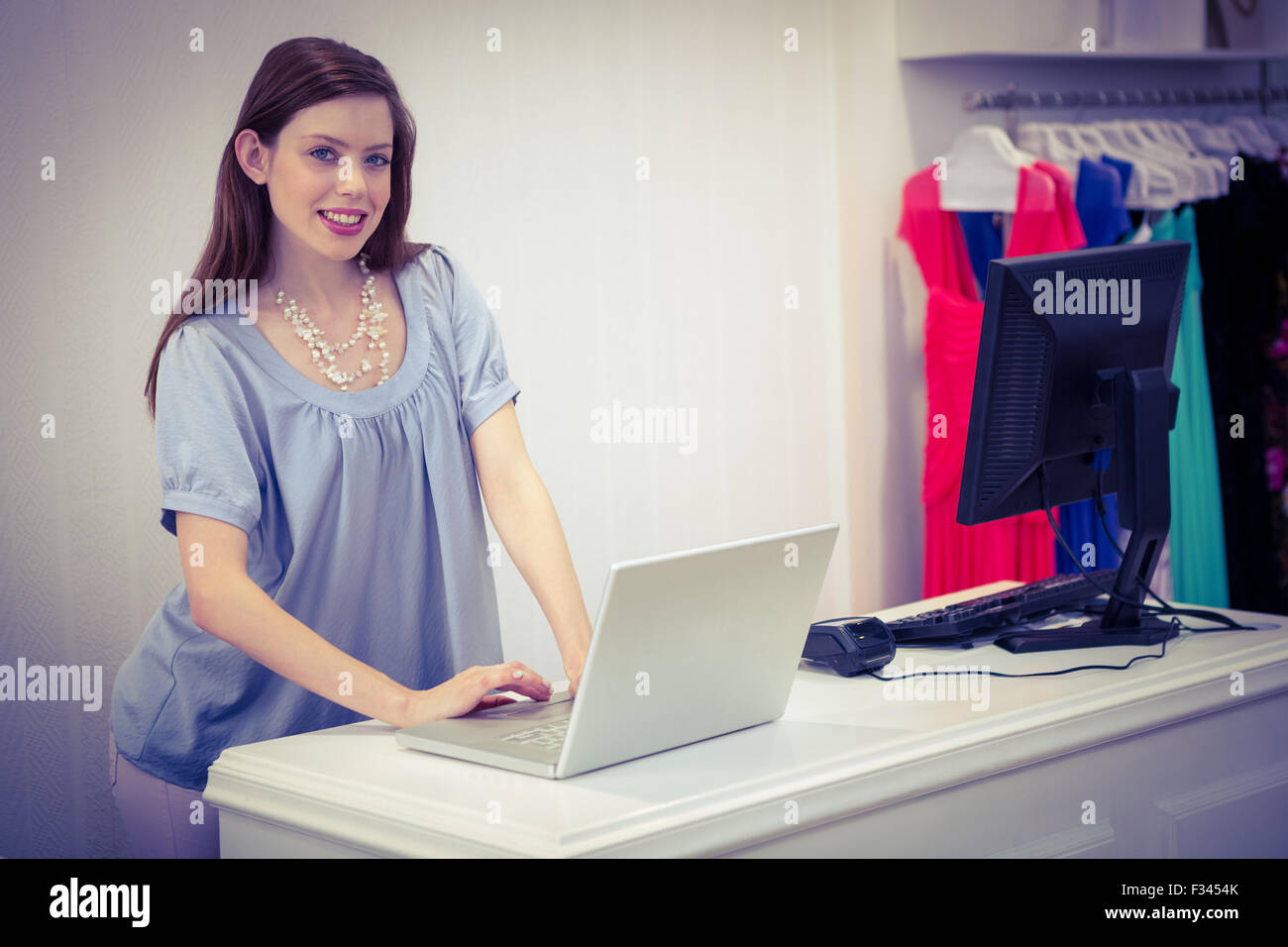 Shop worker using laptop by the till Stock Photo - Alamy