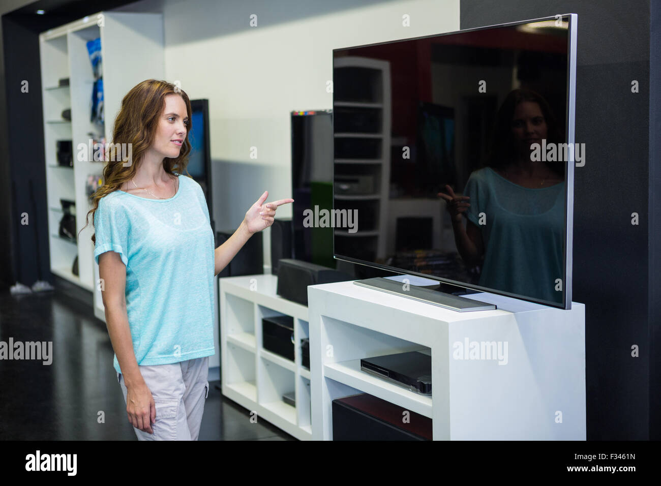 Pretty young woman pointing tv hi-res stock photography and images - Alamy