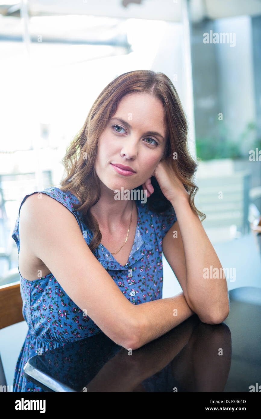 Pretty brunette thinking at table Stock Photo - Alamy