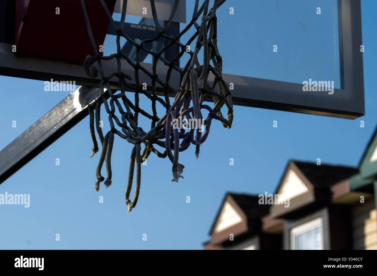 torn basketball net with a red rim and glass backdrop against a deep ...