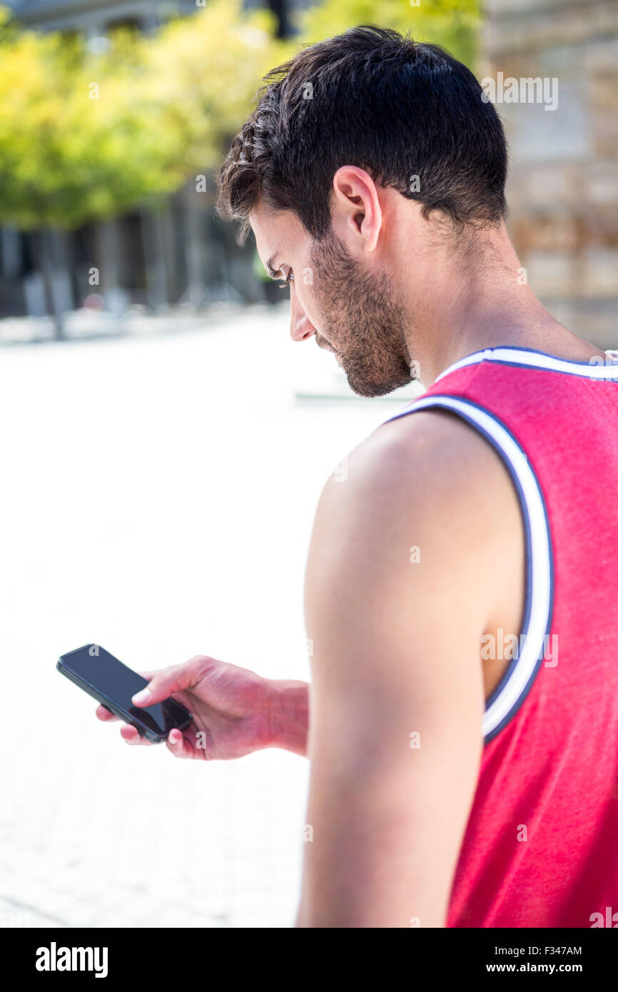 Rear view of an handsome athlete sending a text Stock Photo - Alamy