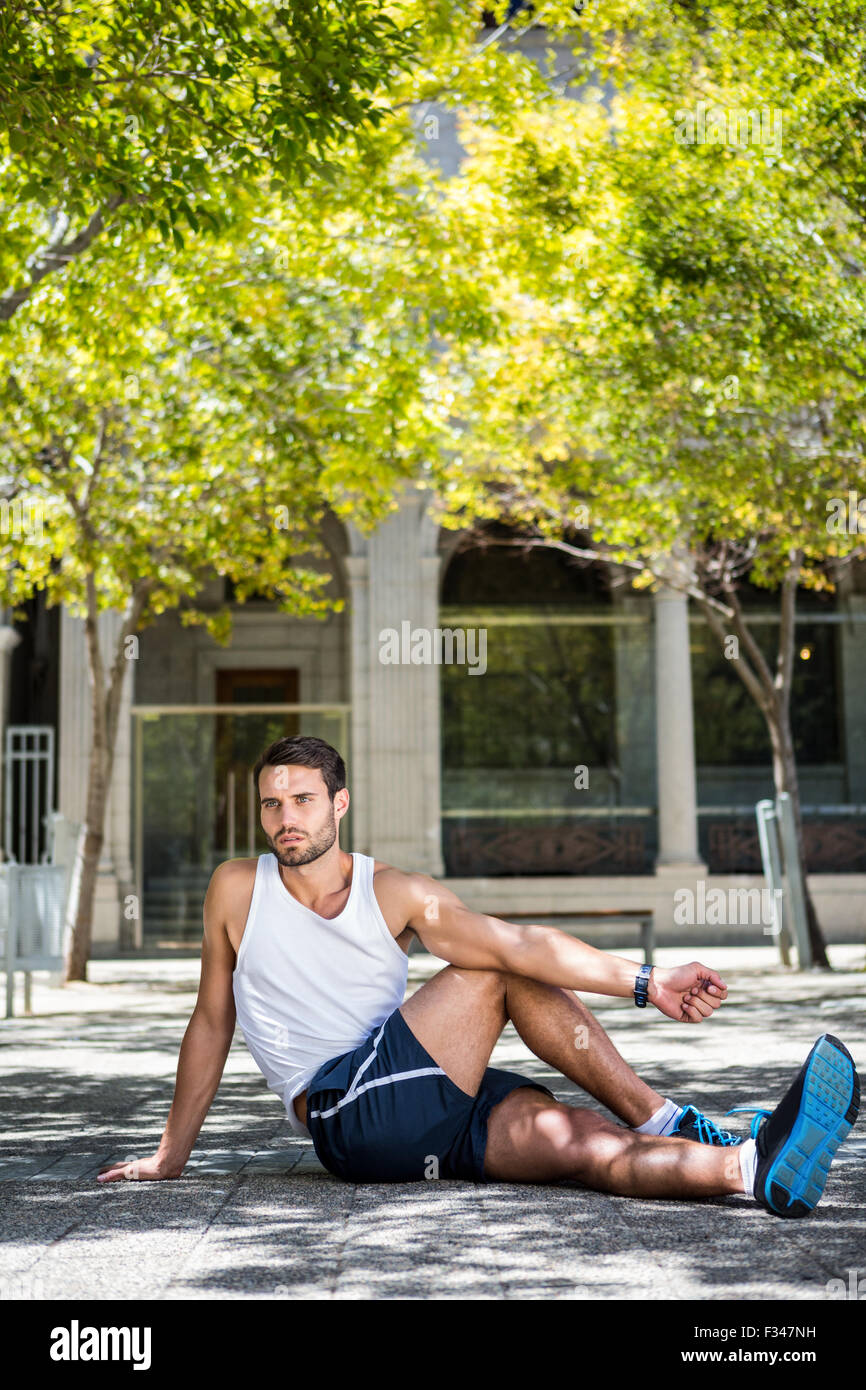 Handsome athlete stretching his leg on the ground Stock Photo - Alamy