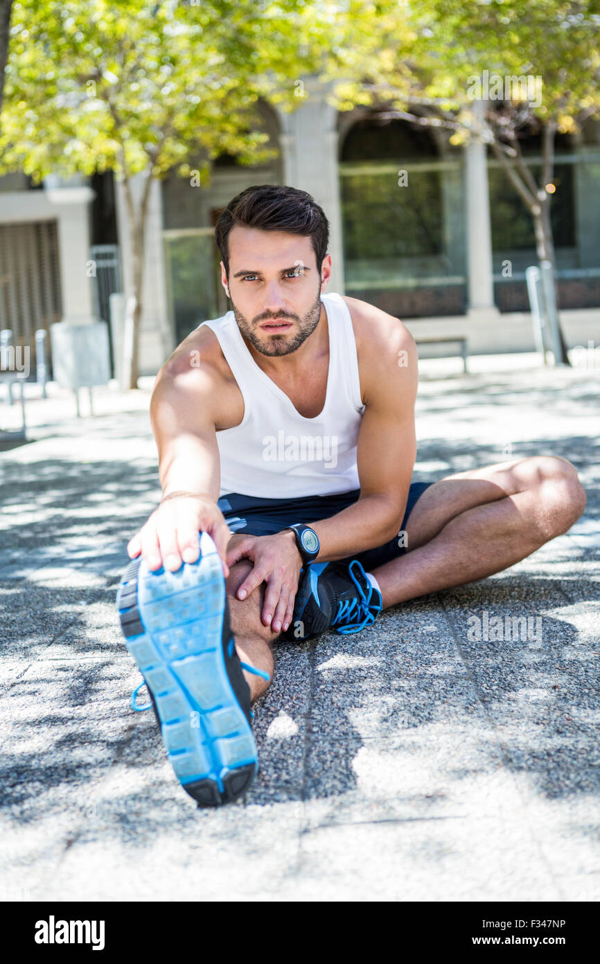 Handsome athlete sitting and stretching his leg Stock Photo - Alamy