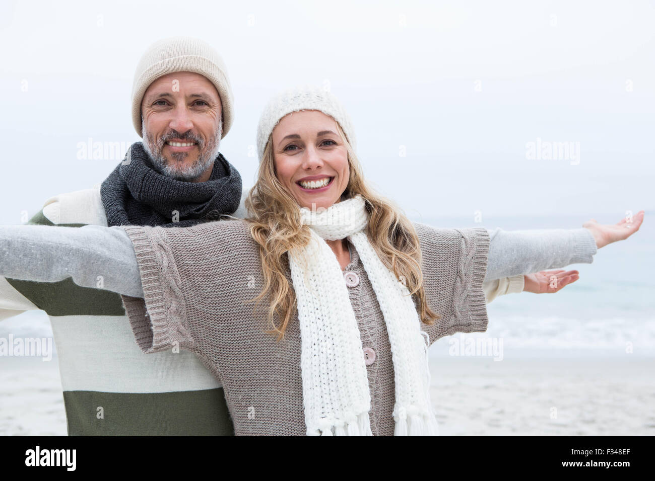 Cute couple standing with arms open wide Stock Photo - Alamy