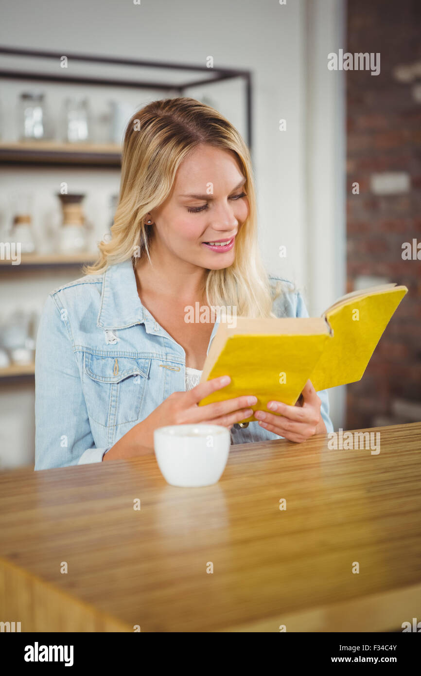 Smiling blonde reading yellow book Stock Photo - Alamy