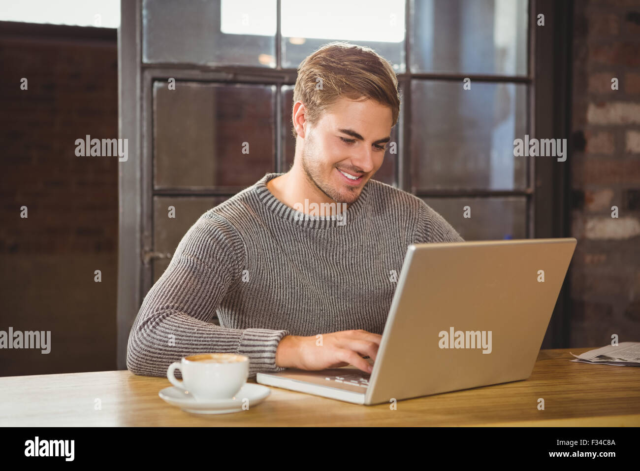 Handsome man smiling and typing on laptop Stock Photo - Alamy