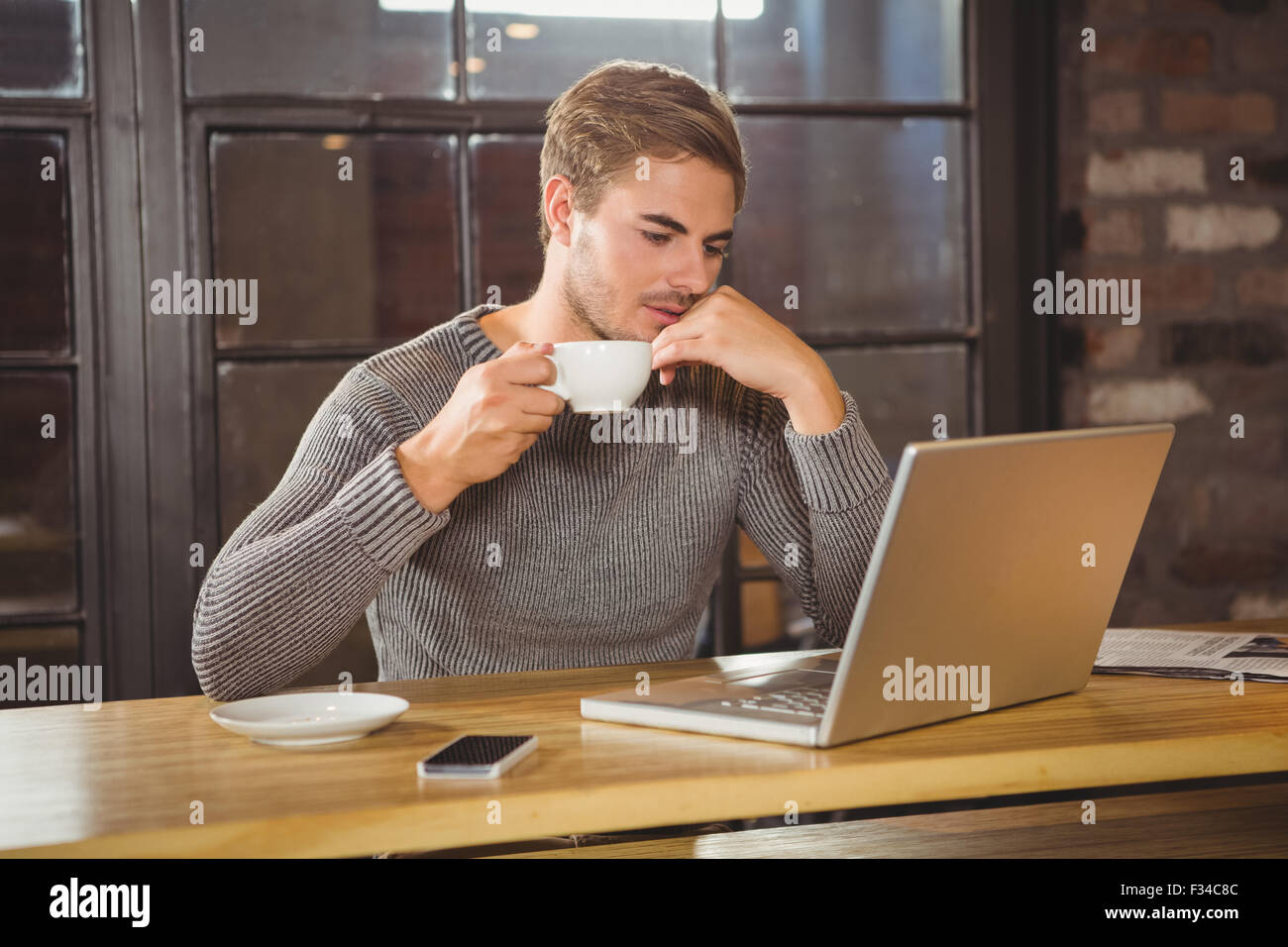 Handsome man drinking coffee and concentrating on laptop Stock Photo ...