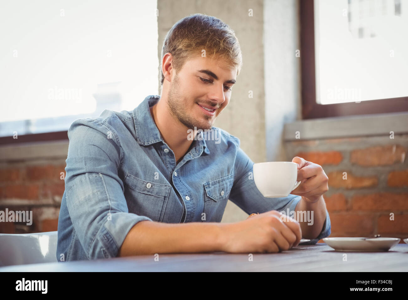 Handsome man smiling and drinking coffee Stock Photo - Alamy