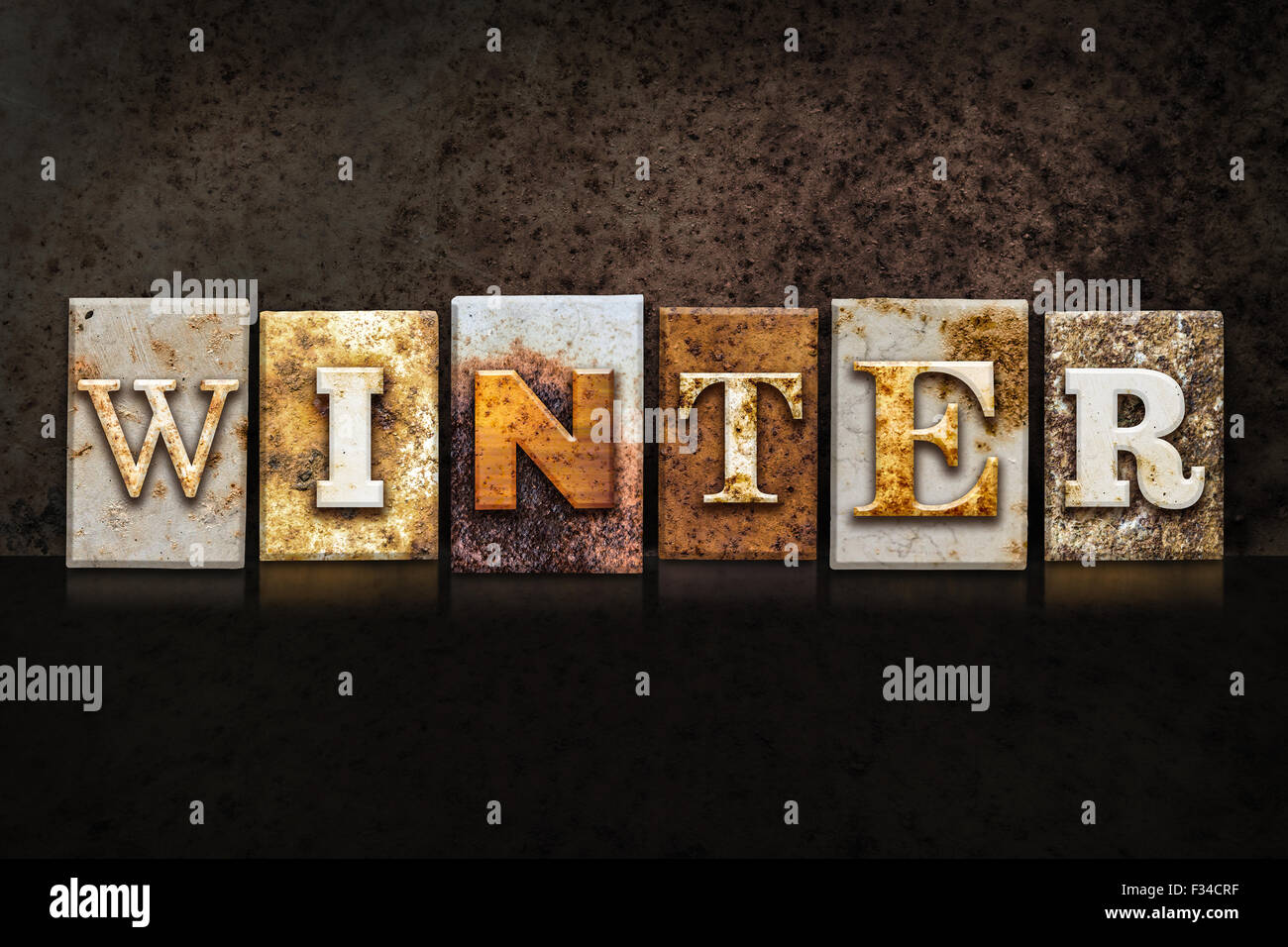 The word "WINTER" written in rusty metal letterpress type on a dark ...