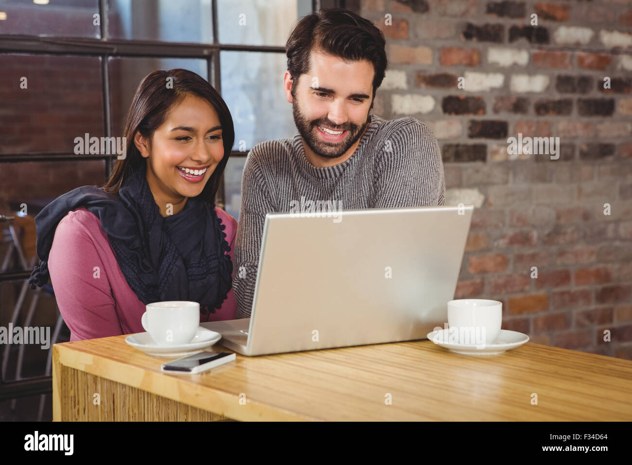 Young happy couple looking at a laptop Stock Photo - Alamy