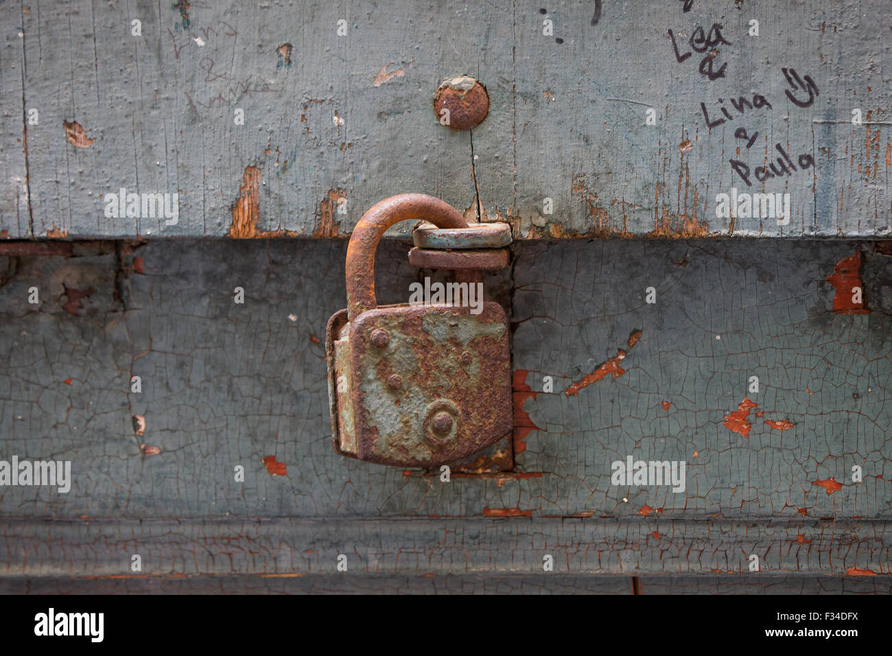 Close-up of a rusty and aged padlock on a weathered wall, viewed from ...