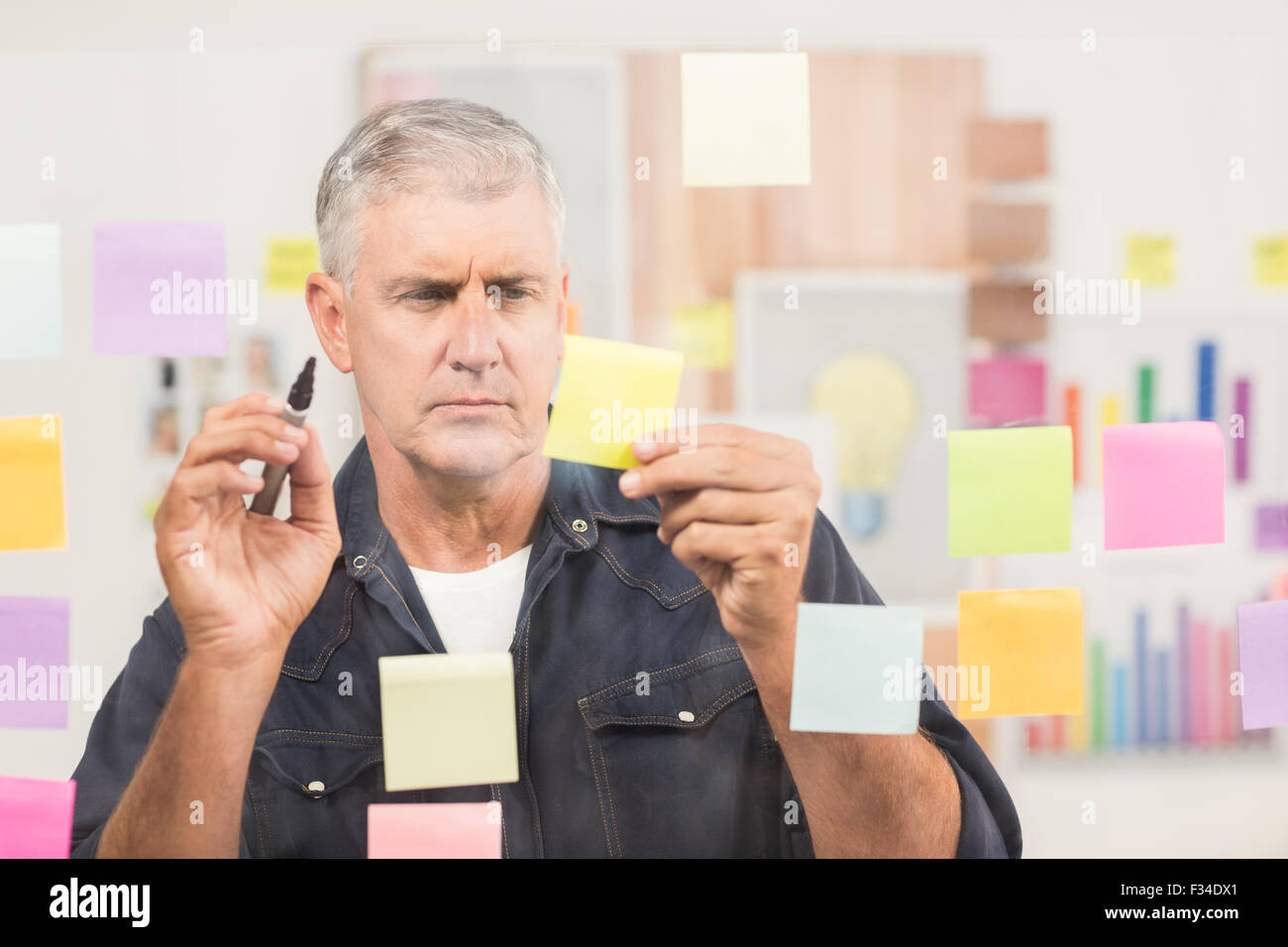 Casual businessman writing on post its Stock Photo - Alamy