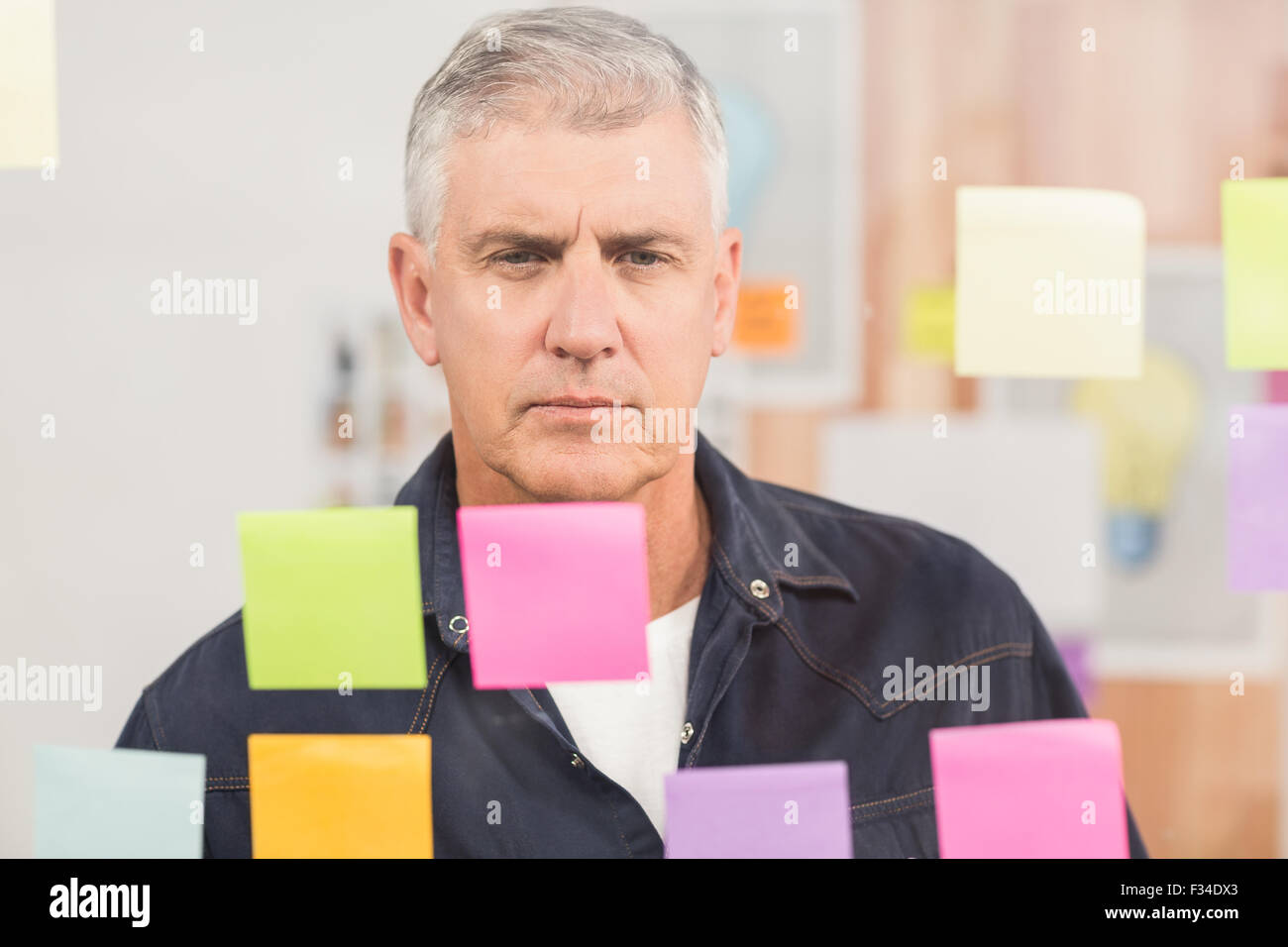 Casual businessman looking at a post it wall Stock Photo - Alamy