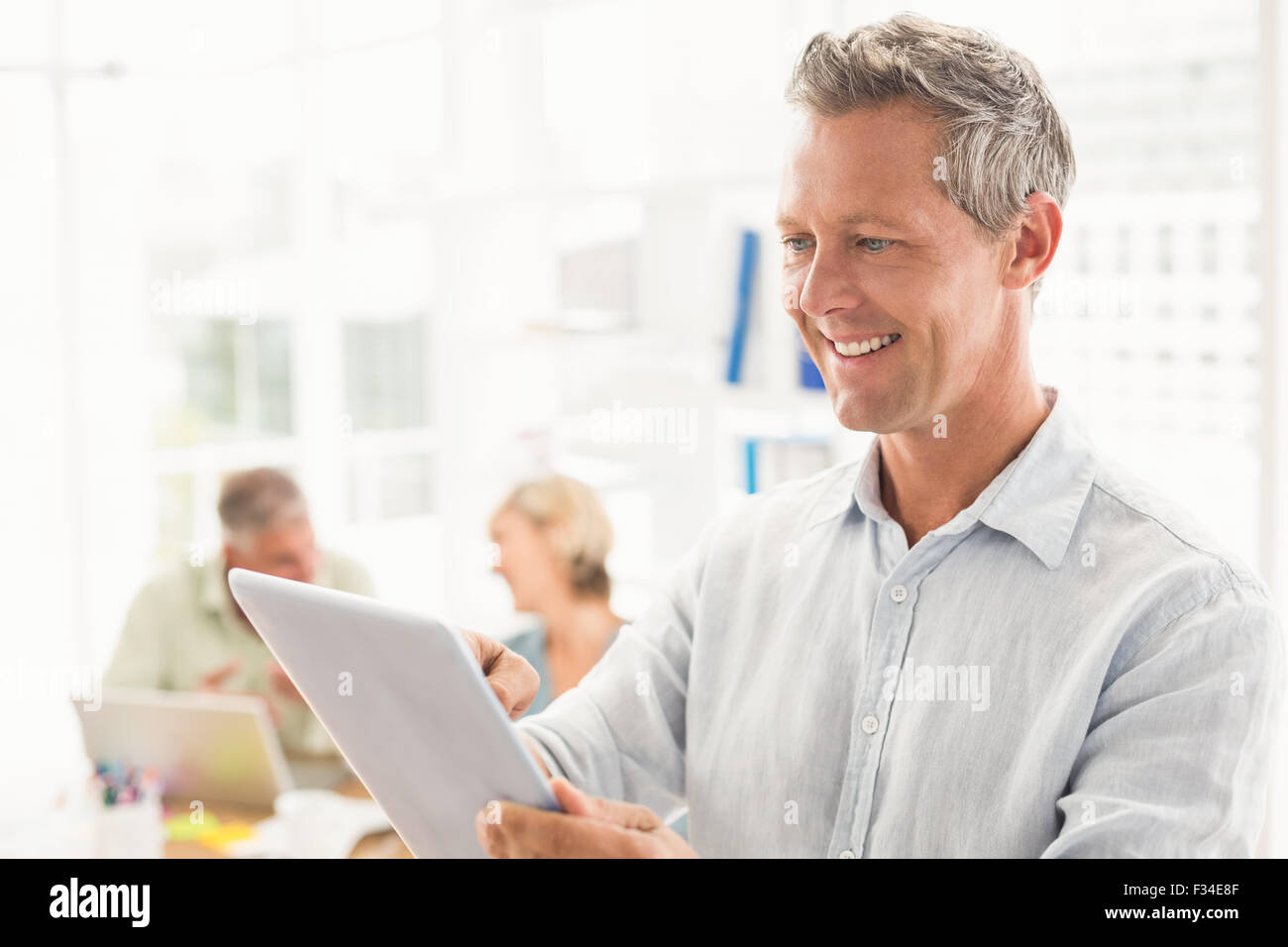 Smiling businessman scrolling on a tablet Stock Photo - Alamy