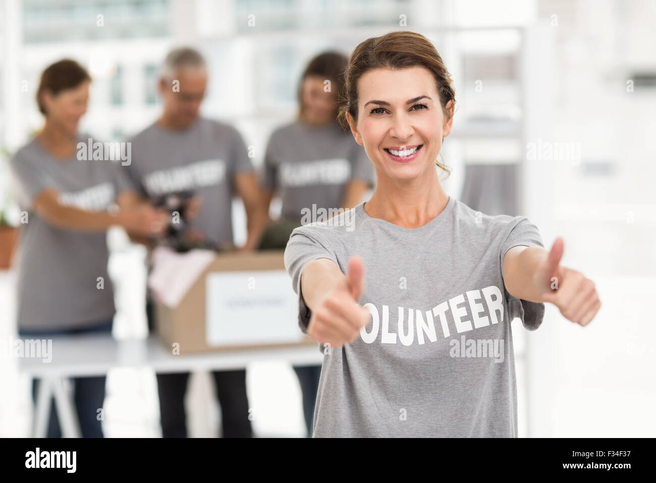 Smiling female volunteer doing thumbs up Stock Photo - Alamy