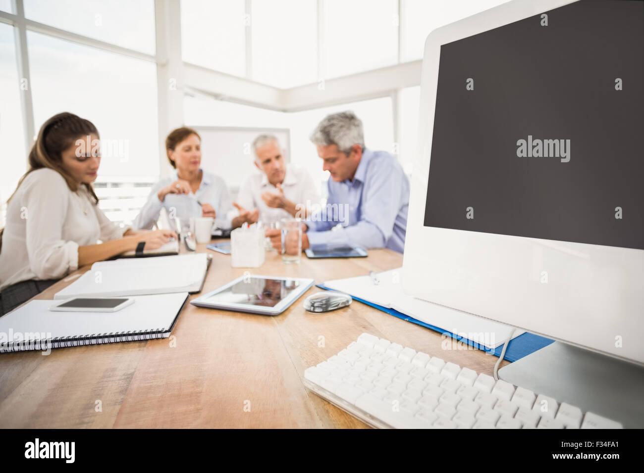 Electronic devices in front of talking business people Stock Photo - Alamy