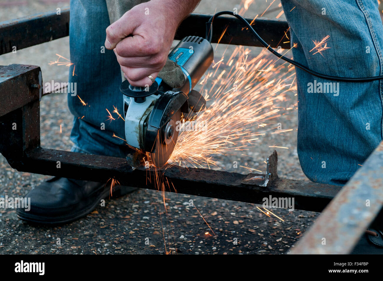 A person angle grinding a boat trailer Stock Photo - Alamy