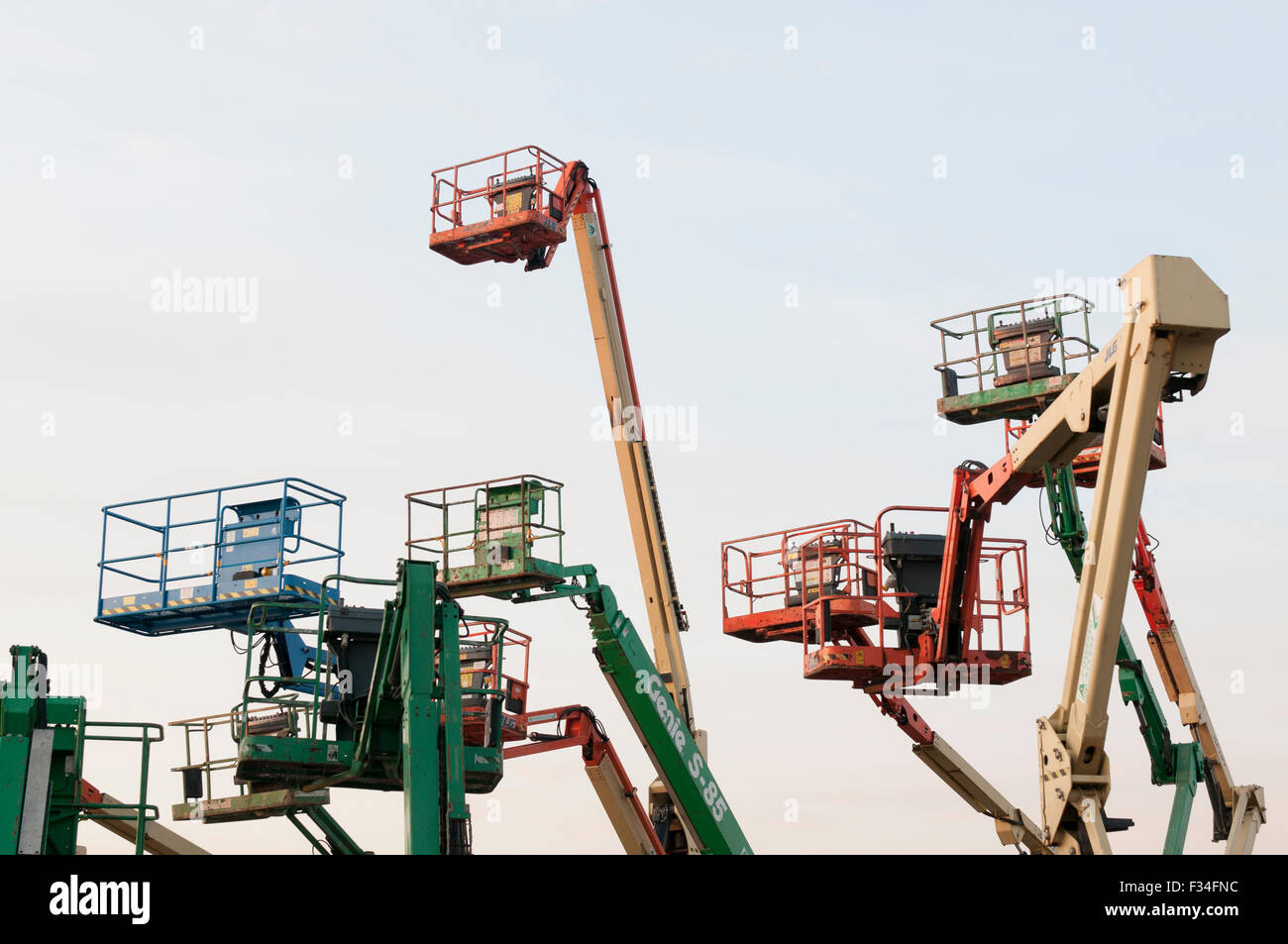 A group of empty boom lifted empty cherry picker cages set against a ...