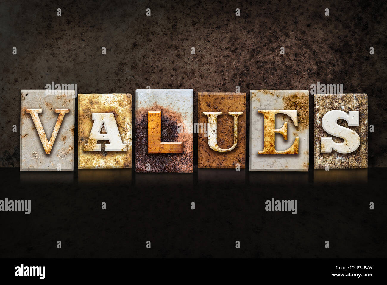 The word "VALUES" written in rusty metal letterpress type on a dark ...