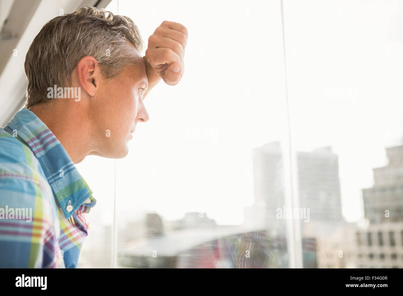 Troubled casual businessman leaning against window Stock Photo - Alamy