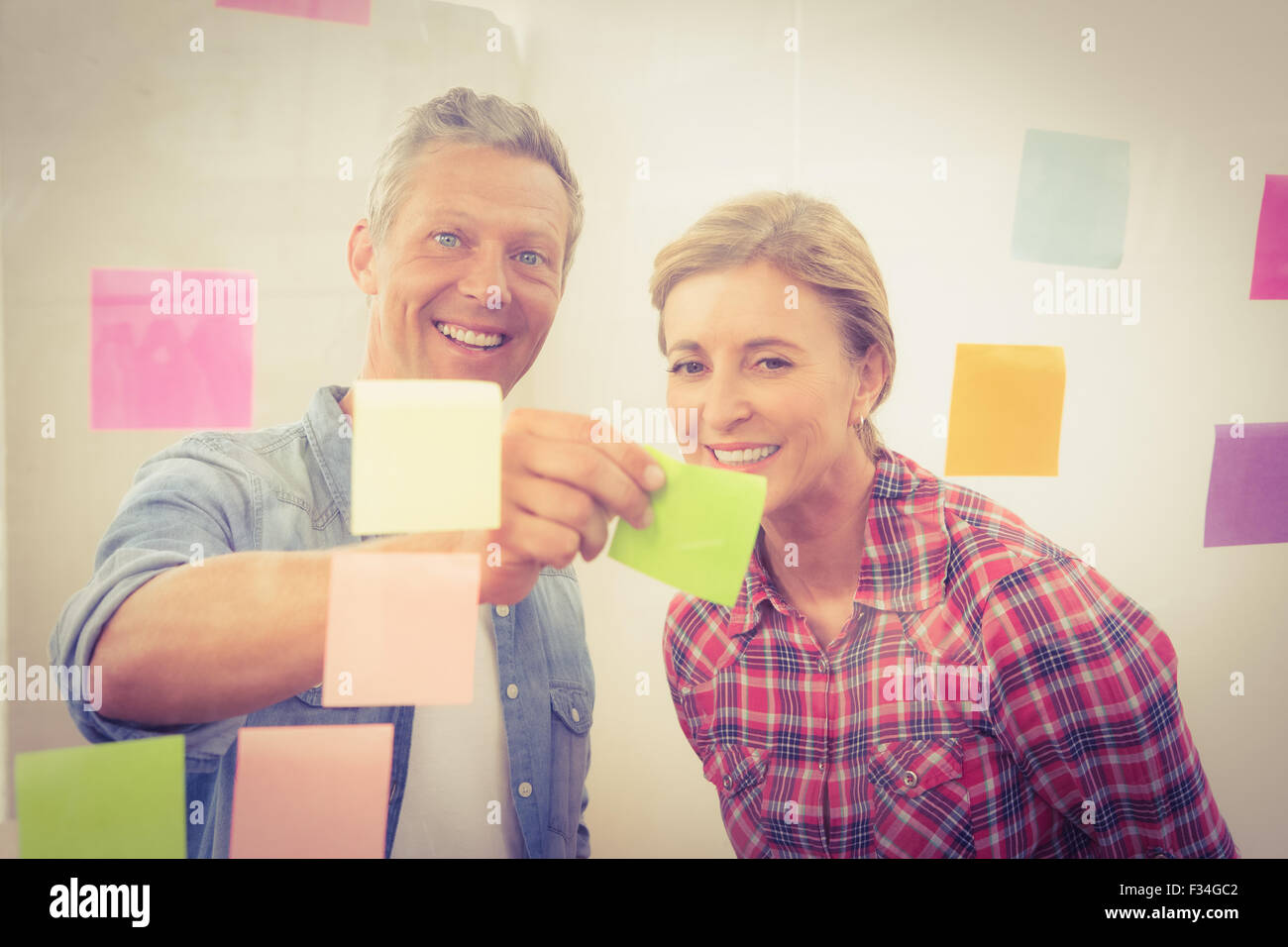 Smiling casual businessman showing sticky note to colleague Stock Photo ...