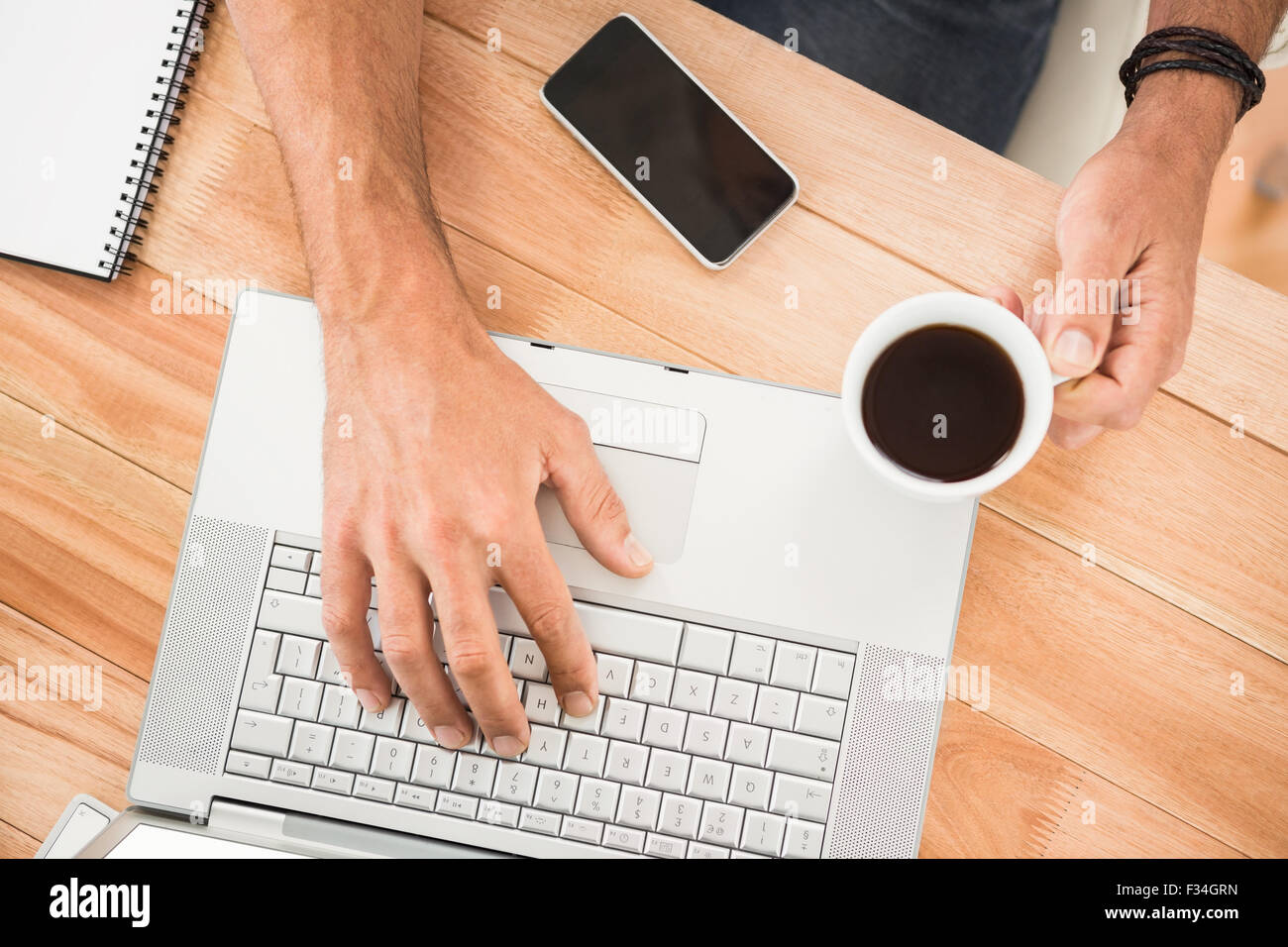Hands holding coffee cup and typing on laptop Stock Photo - Alamy