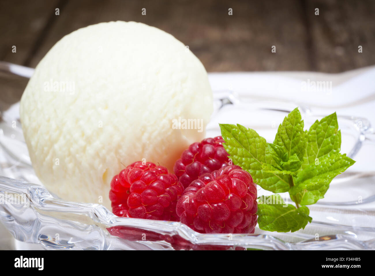 Vanilla ice cream and raspberries garnished with mint leaves in glass ...