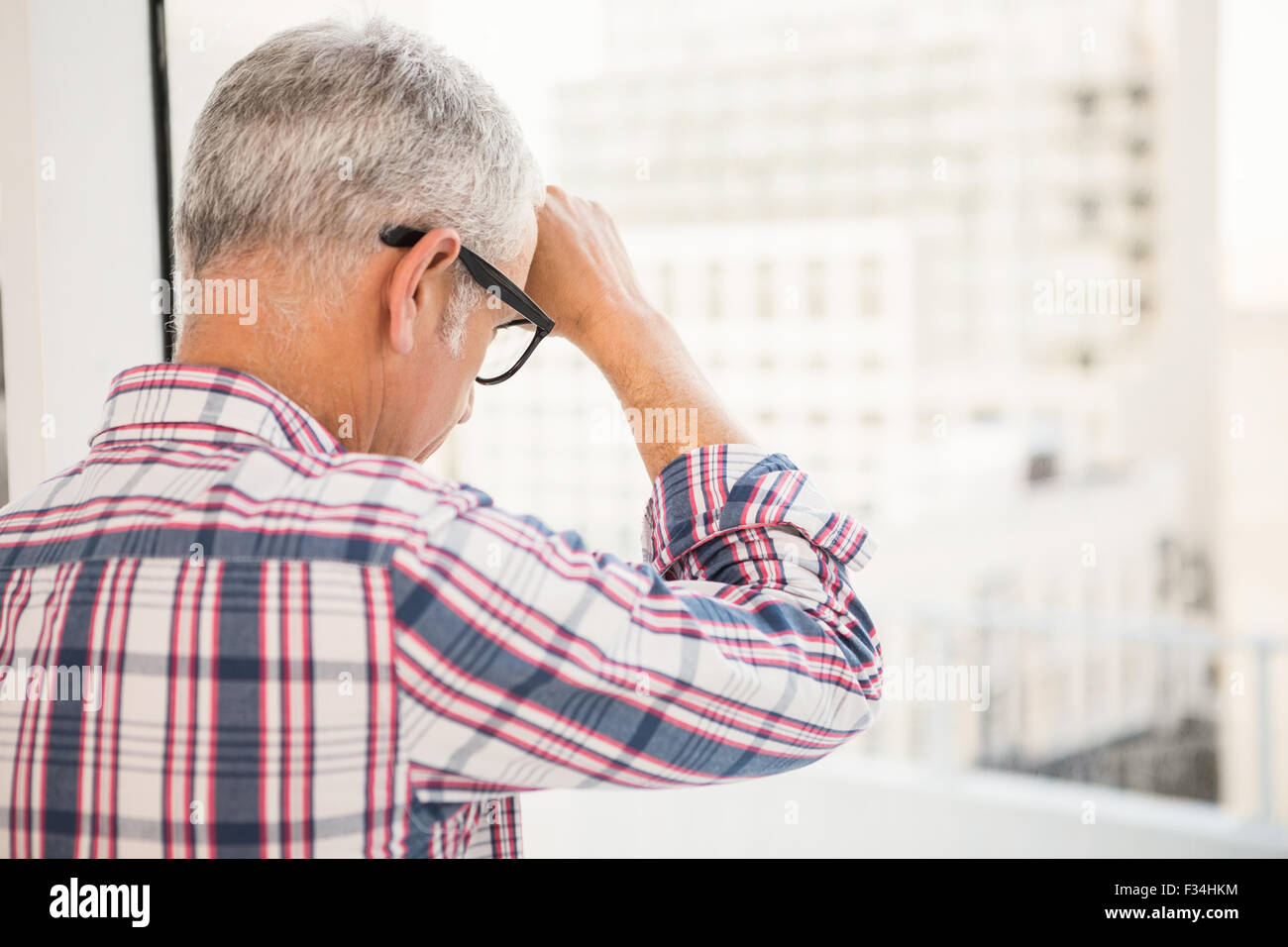 Troubled casual businessman leaning against window Stock Photo - Alamy