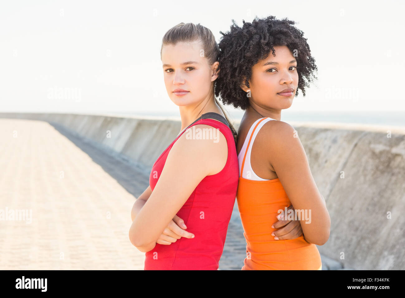 Two young women standing back to back Stock Photo - Alamy