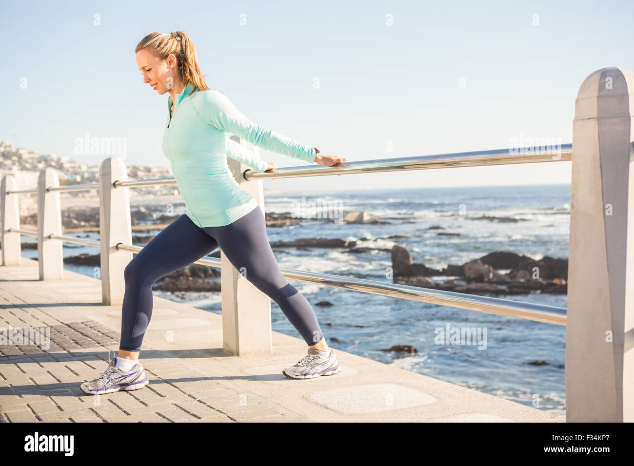 Fit blonde stretching on railing Stock Photo - Alamy