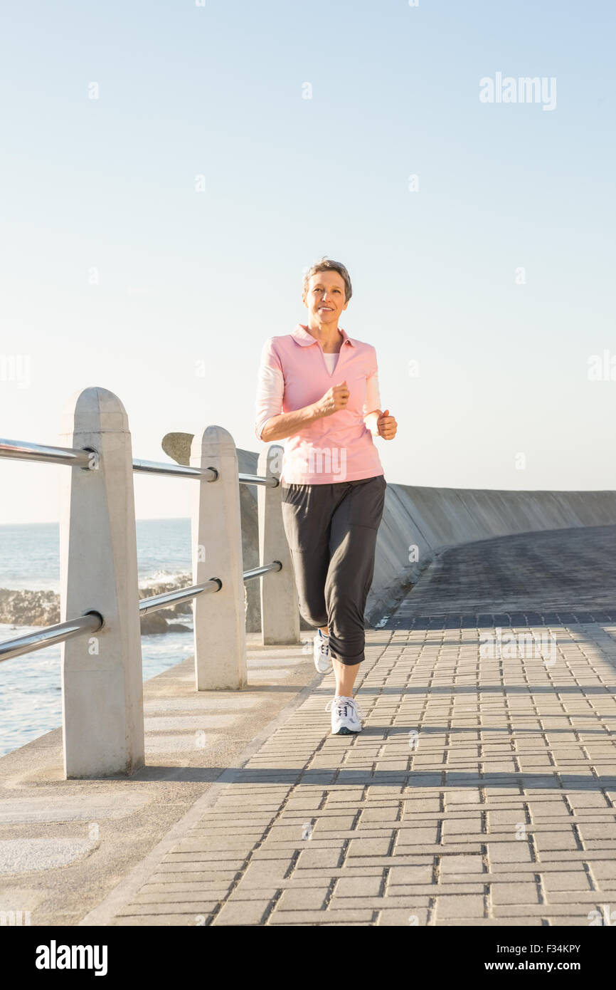 Smiling sporty woman jogging at promenade Stock Photo - Alamy